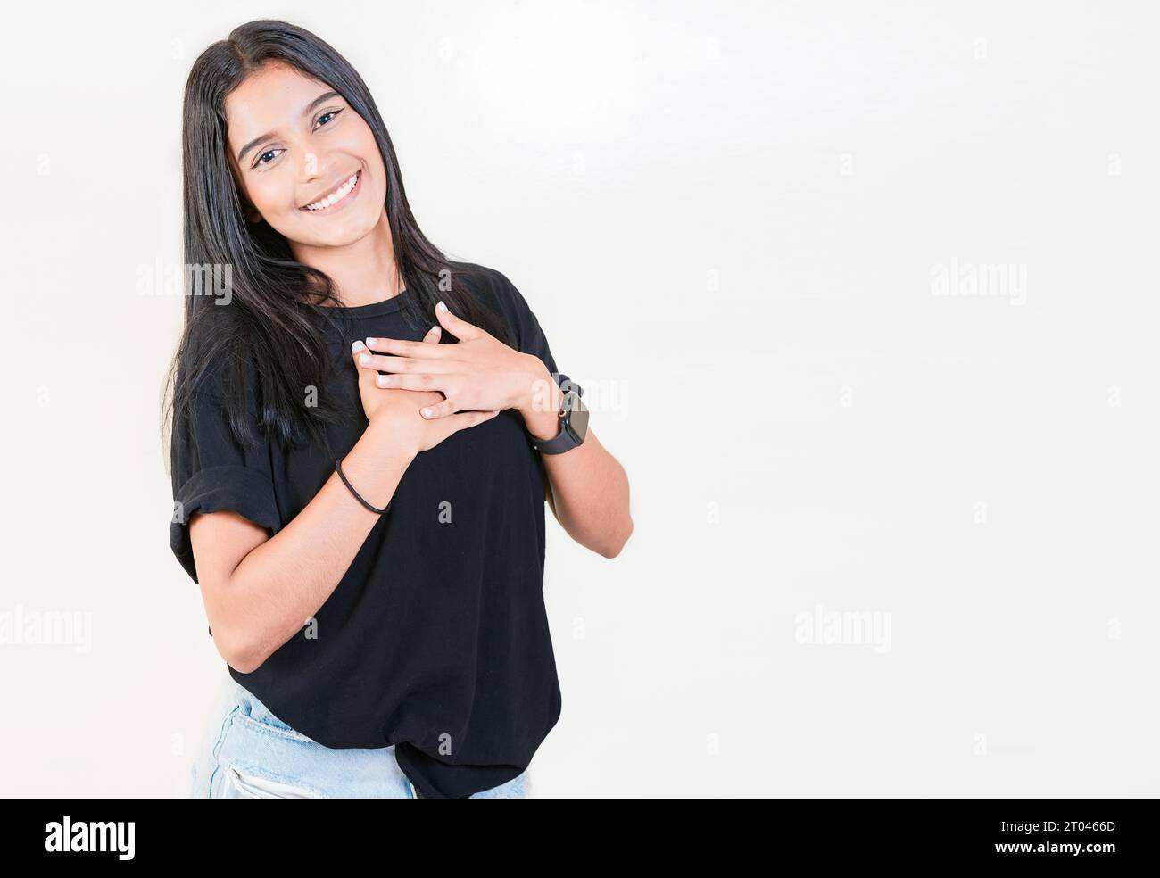 Grateful teenage girl smiling with hands on chest isolated. Positive ...