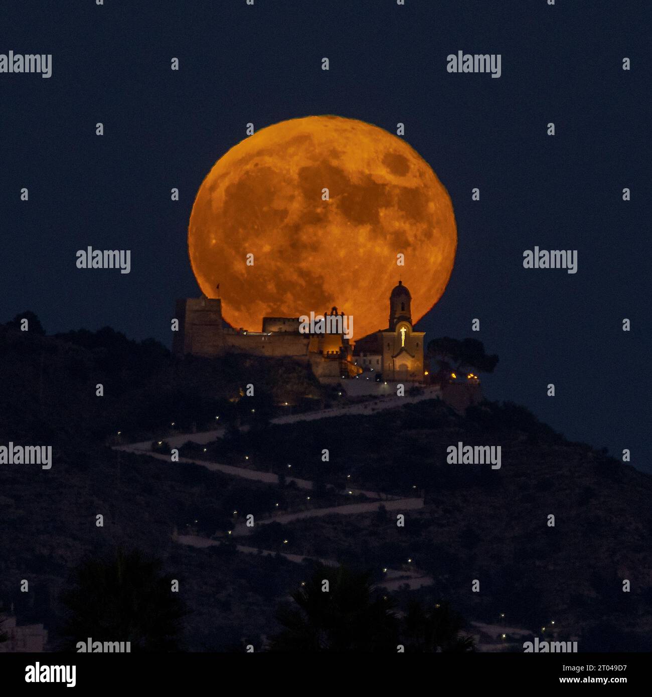 A scenic view of supermoon behind an old church on the hill at night ...