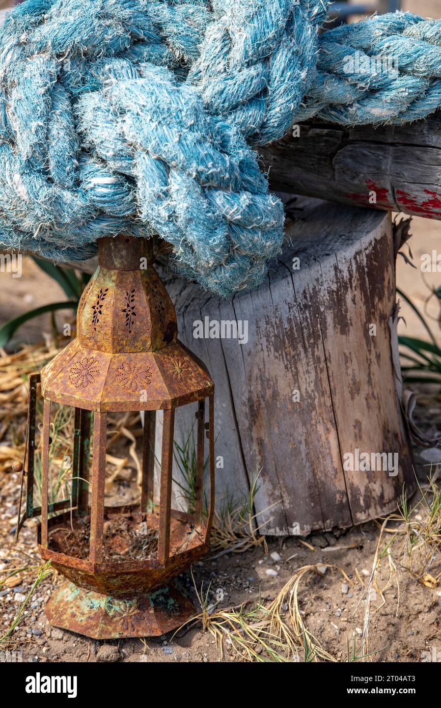 rusty old ships lantern and weathered blue rope washed up on a beach ...