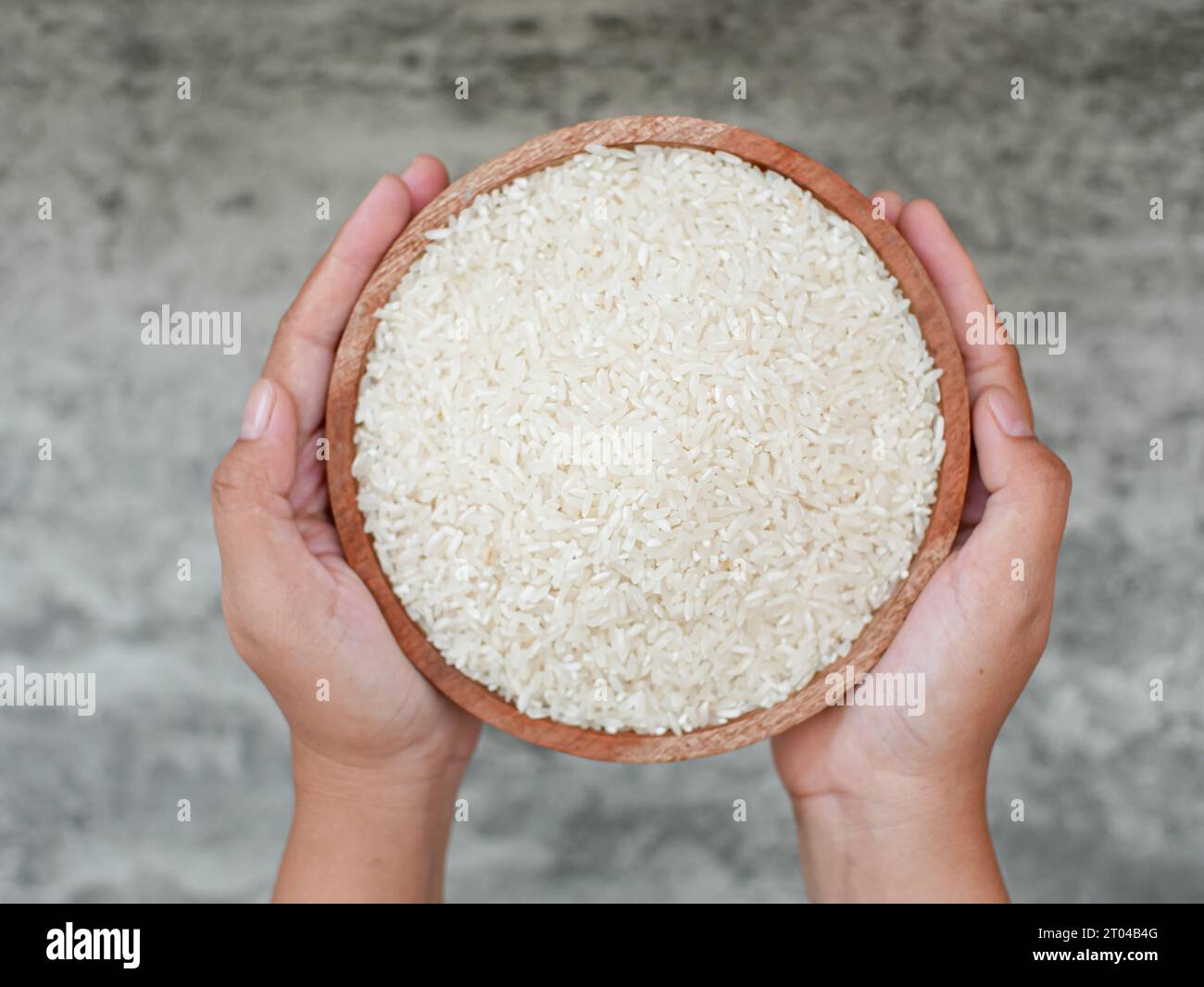 Hand holding wooden bowl filled with rice grains for zakat, concept of ...