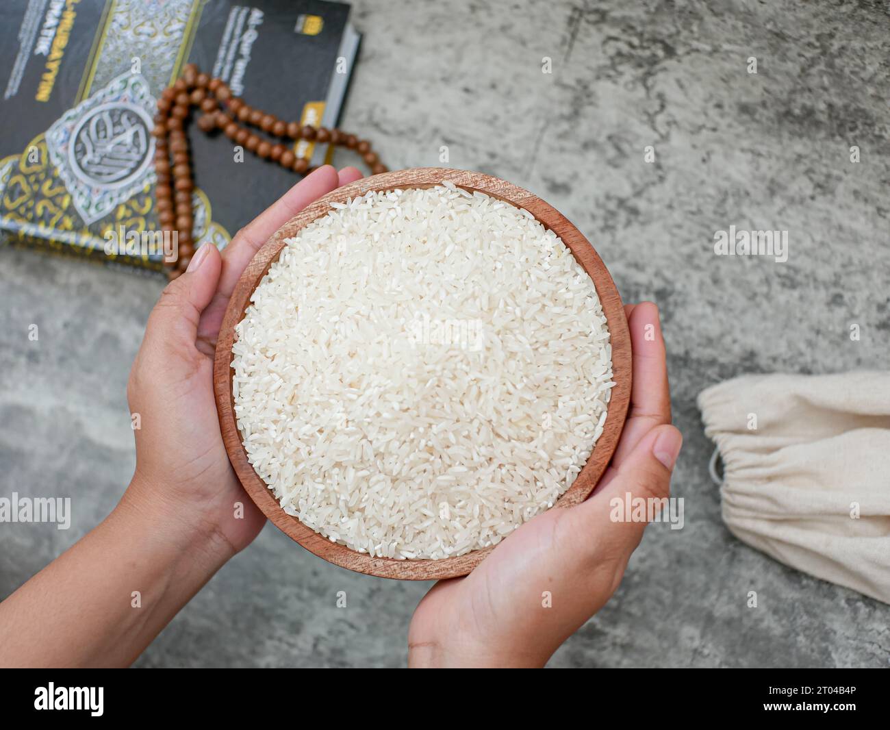 Hand Holding Wooden Bowl Filled With Rice Grains For Zakat Concept Of