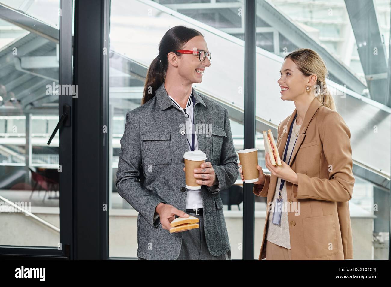stylish team members having lunch break with sandwiches and coffee with ...
