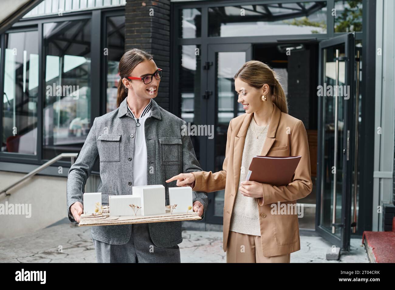 two smiley colleagues discussing scale model holding papers and smiling ...