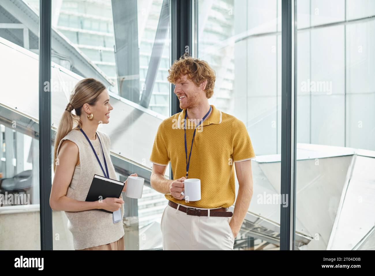 two happy coworkers in smart wear smiling and talking to each other ...