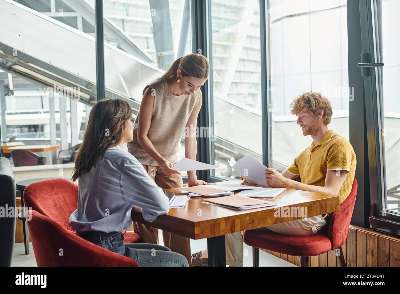 three young colleagues in smart attire working hard with documents with ...