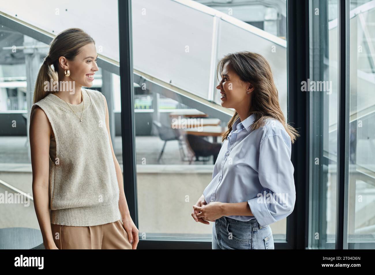 smiling female colleagues in smart casual attire looking at each other ...