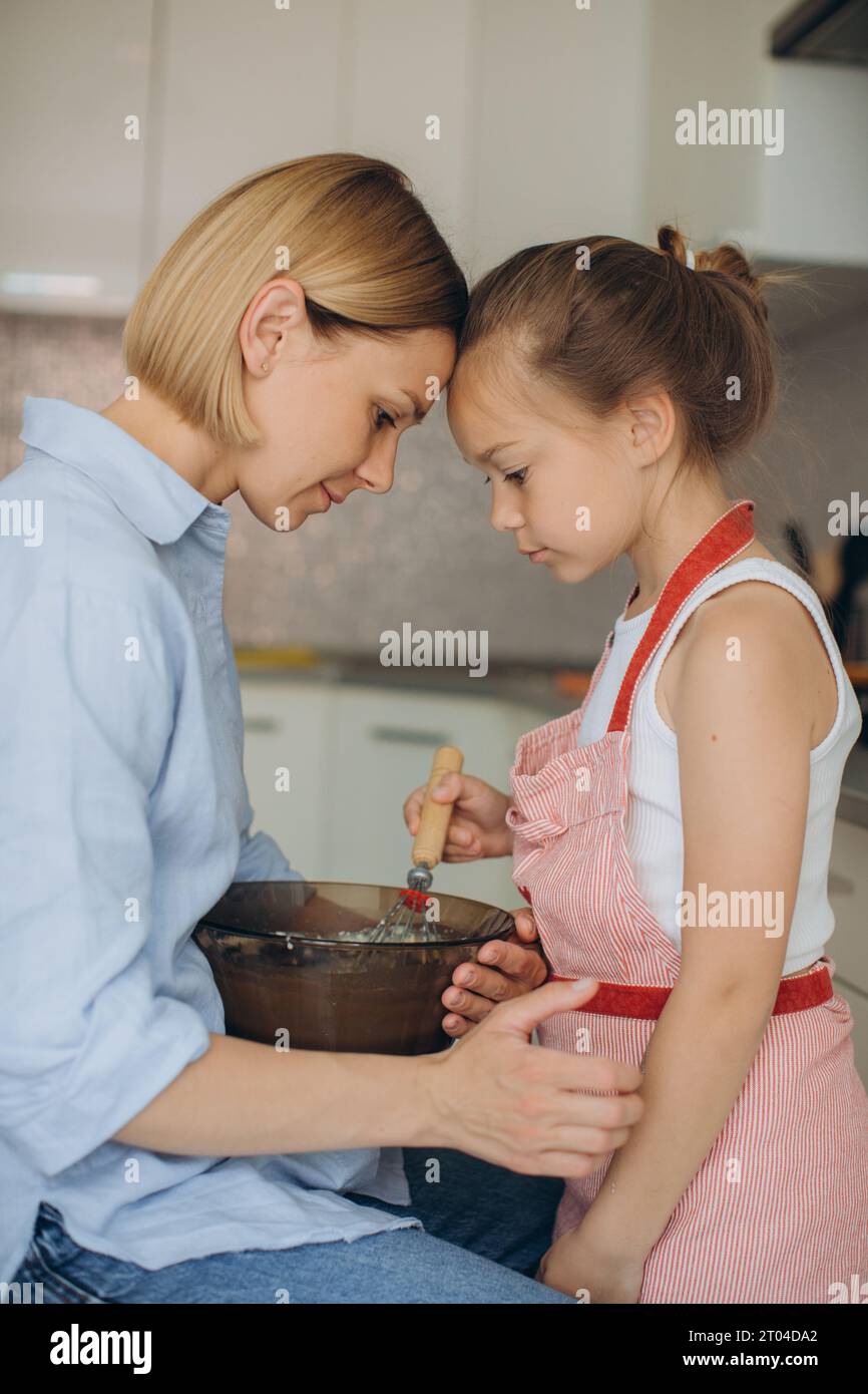 Lifestyle photo, mother with 8-year-old daughter cooking in the kitchen. Mother's day concept ...