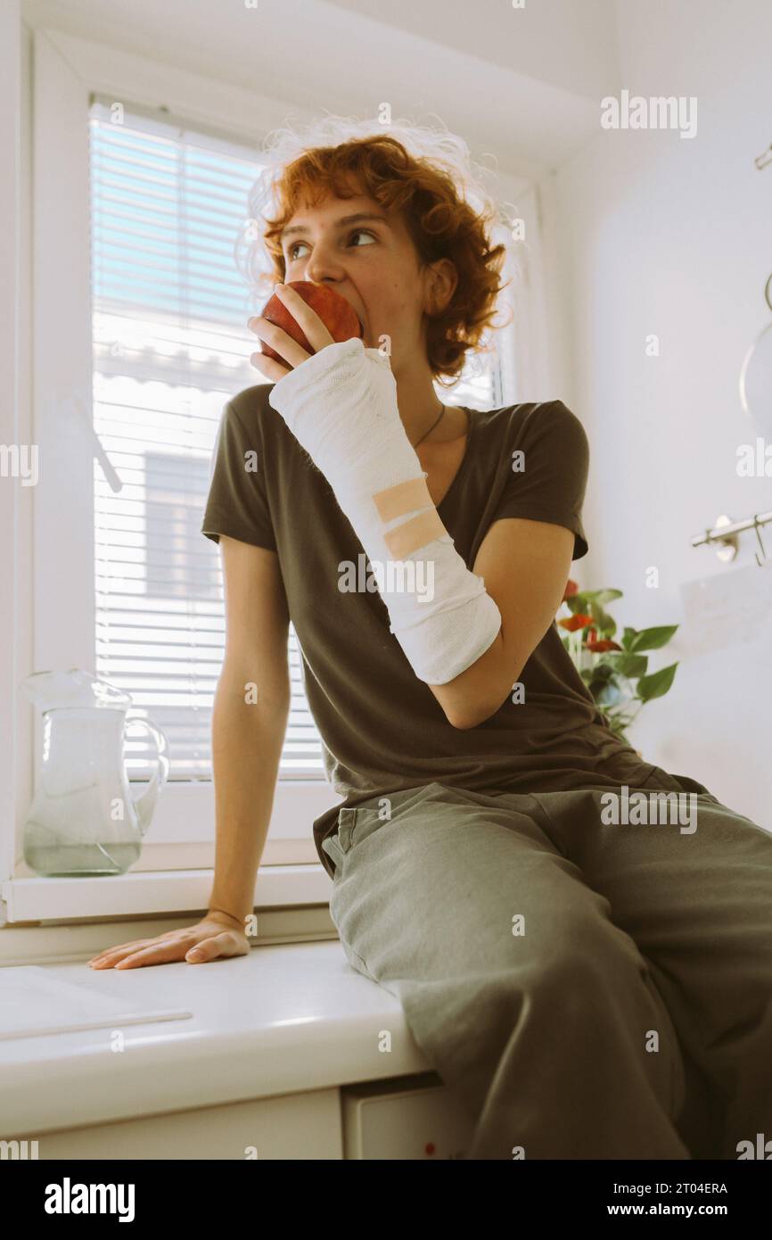teenage girl with broken arm in cast in kitchen sitting on countertop ...