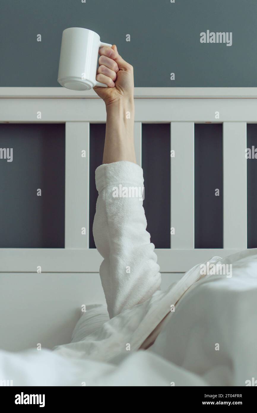 First morning coffee. Unrecognizable man wakes up and stretches in ...