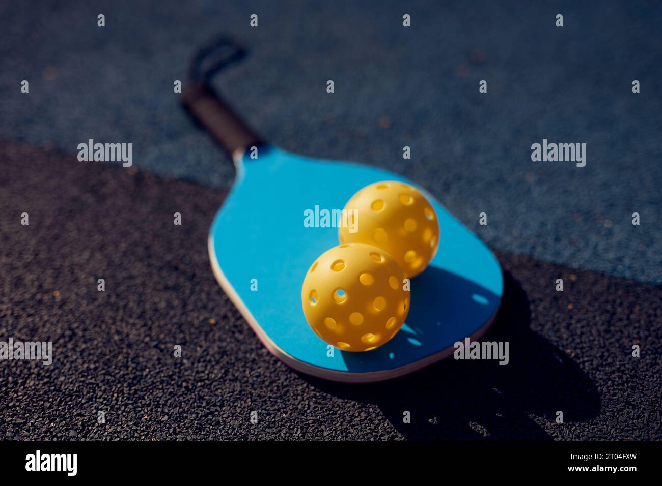 Paddle racket and perforated plastic balls for pickleball lying on ...