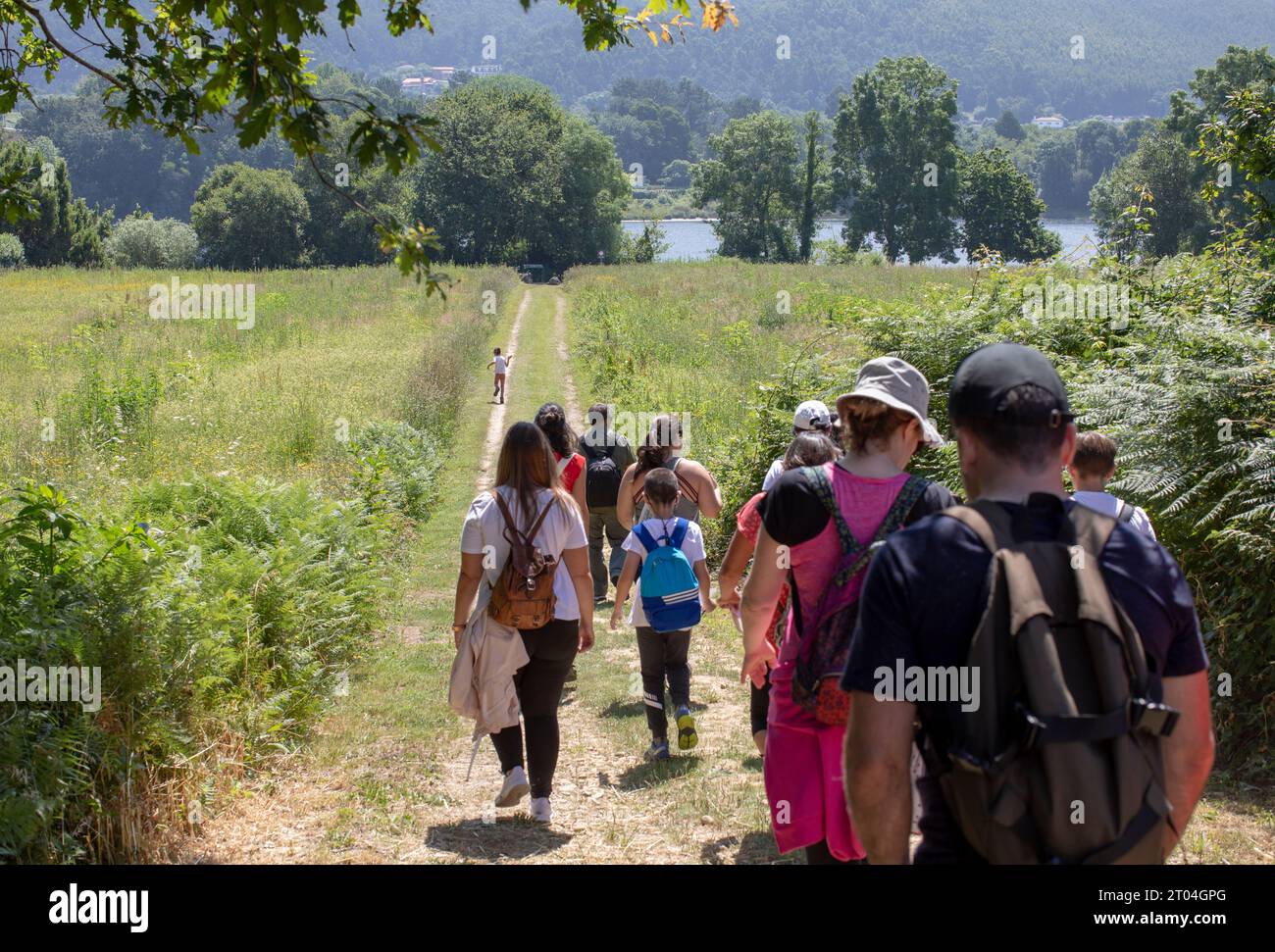 A group of people take a route walking along the banks of the Miño ...