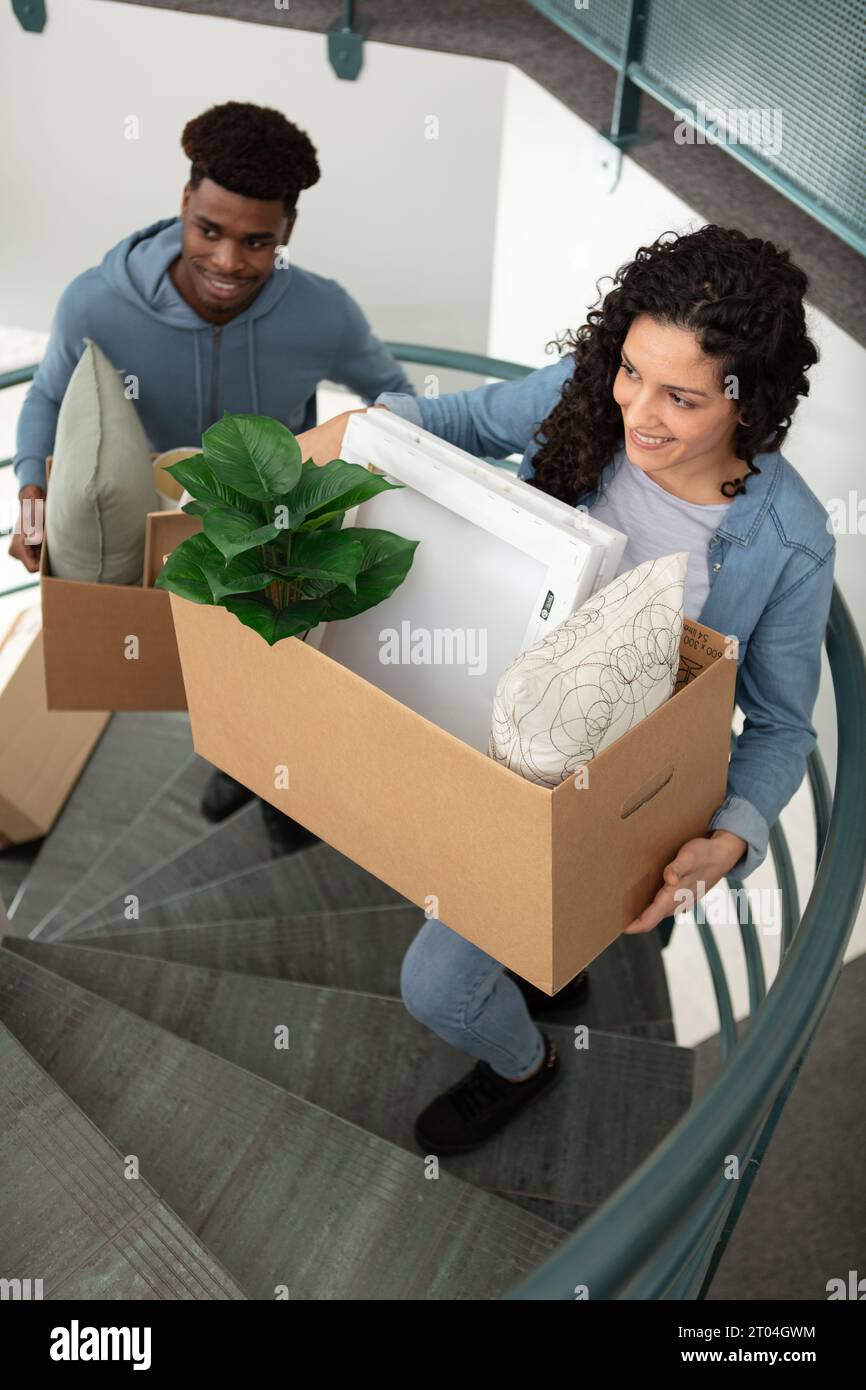 couple going up stairs carrying boxes of possessions Stock Photo - Alamy