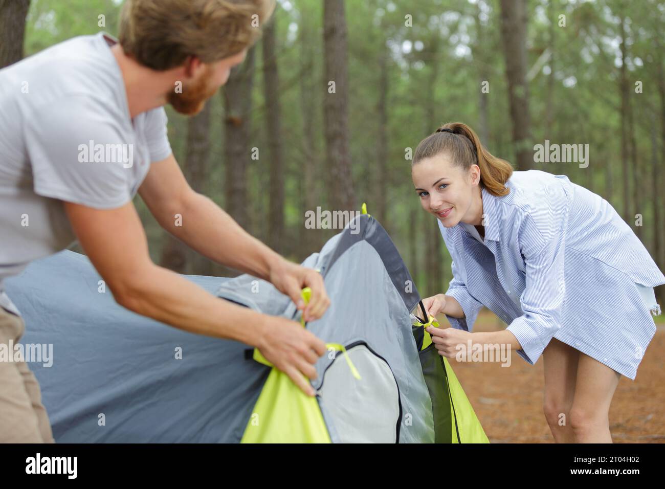 couple making tent while camping in forest Stock Photo - Alamy
