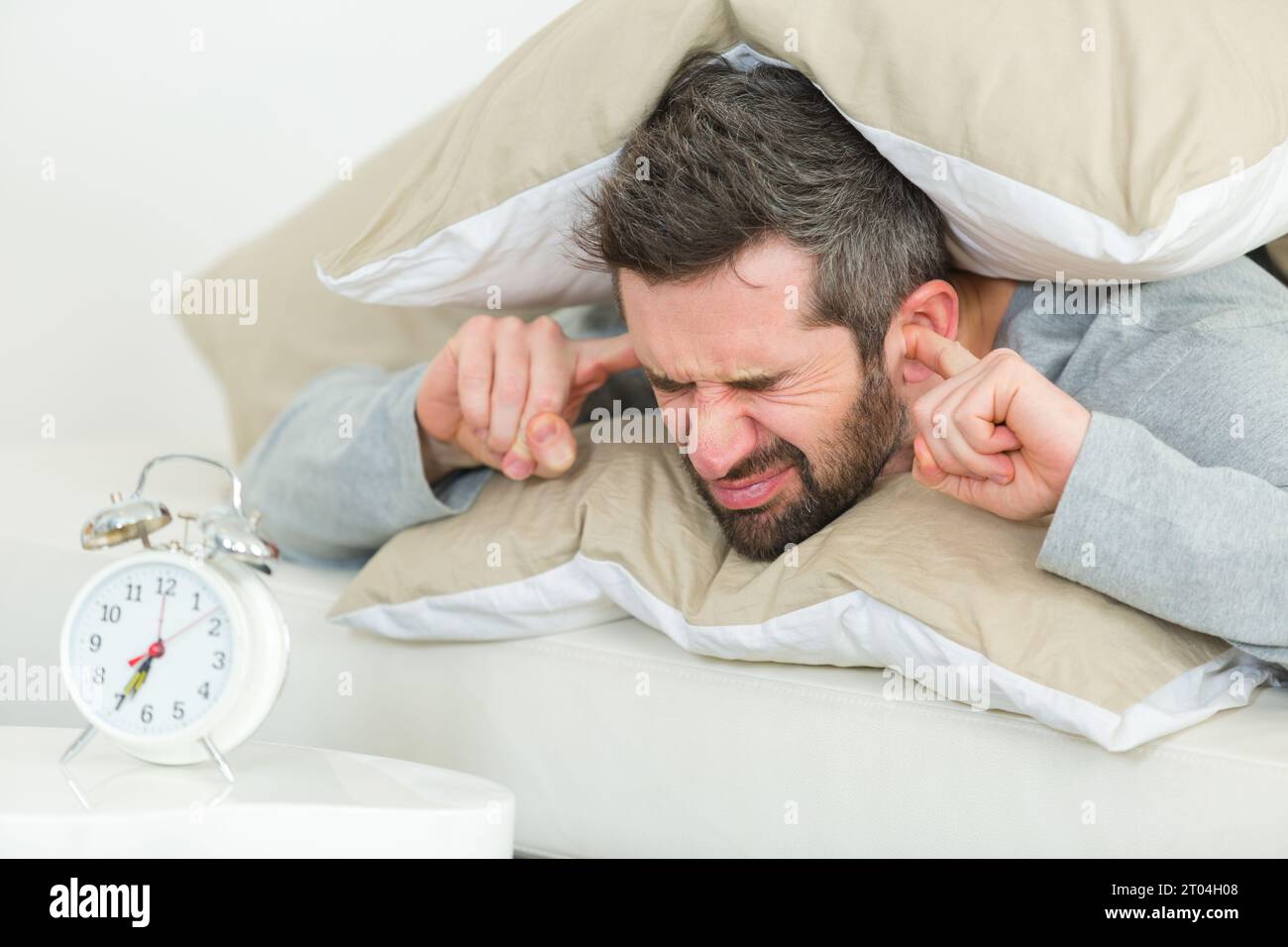 sleepy angry man with alarm clock in the early morning Stock Photo - Alamy