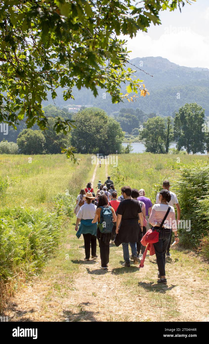A group of people take a route walking along the banks of the Miño ...