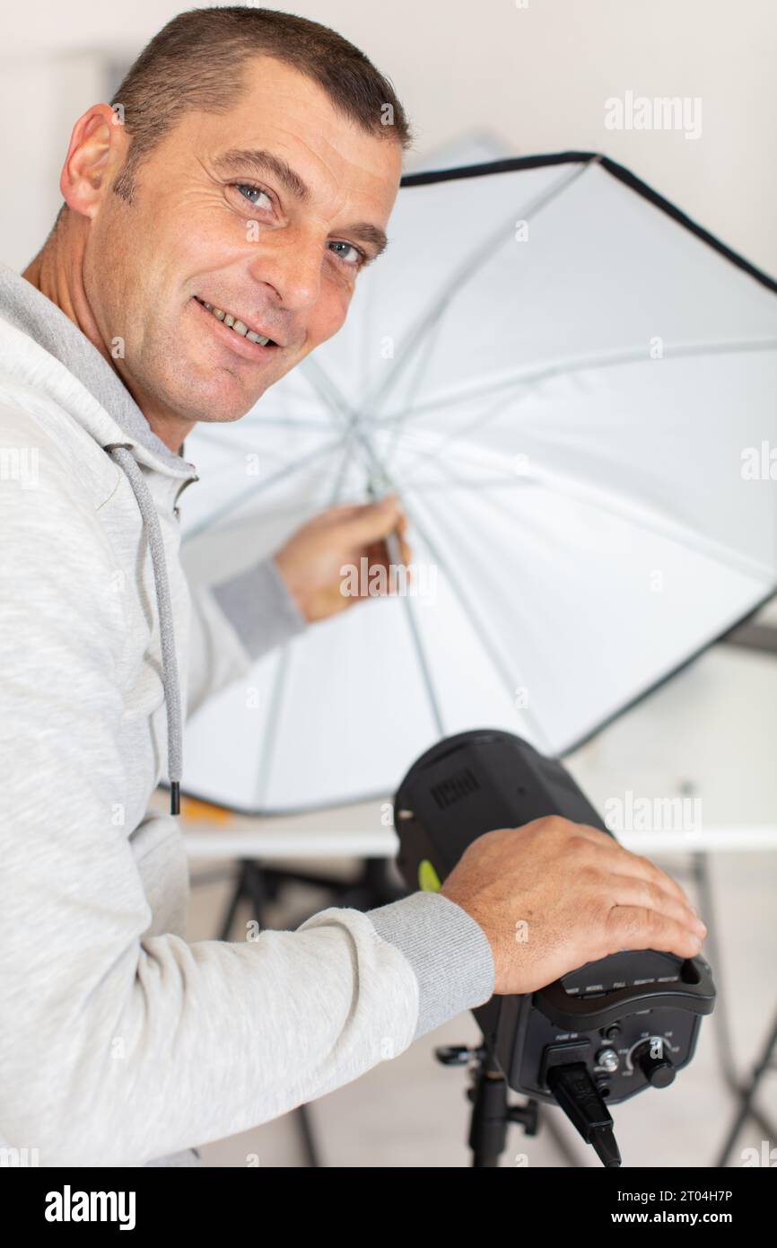 cheerful photographer setting light in photo studio Stock Photo - Alamy