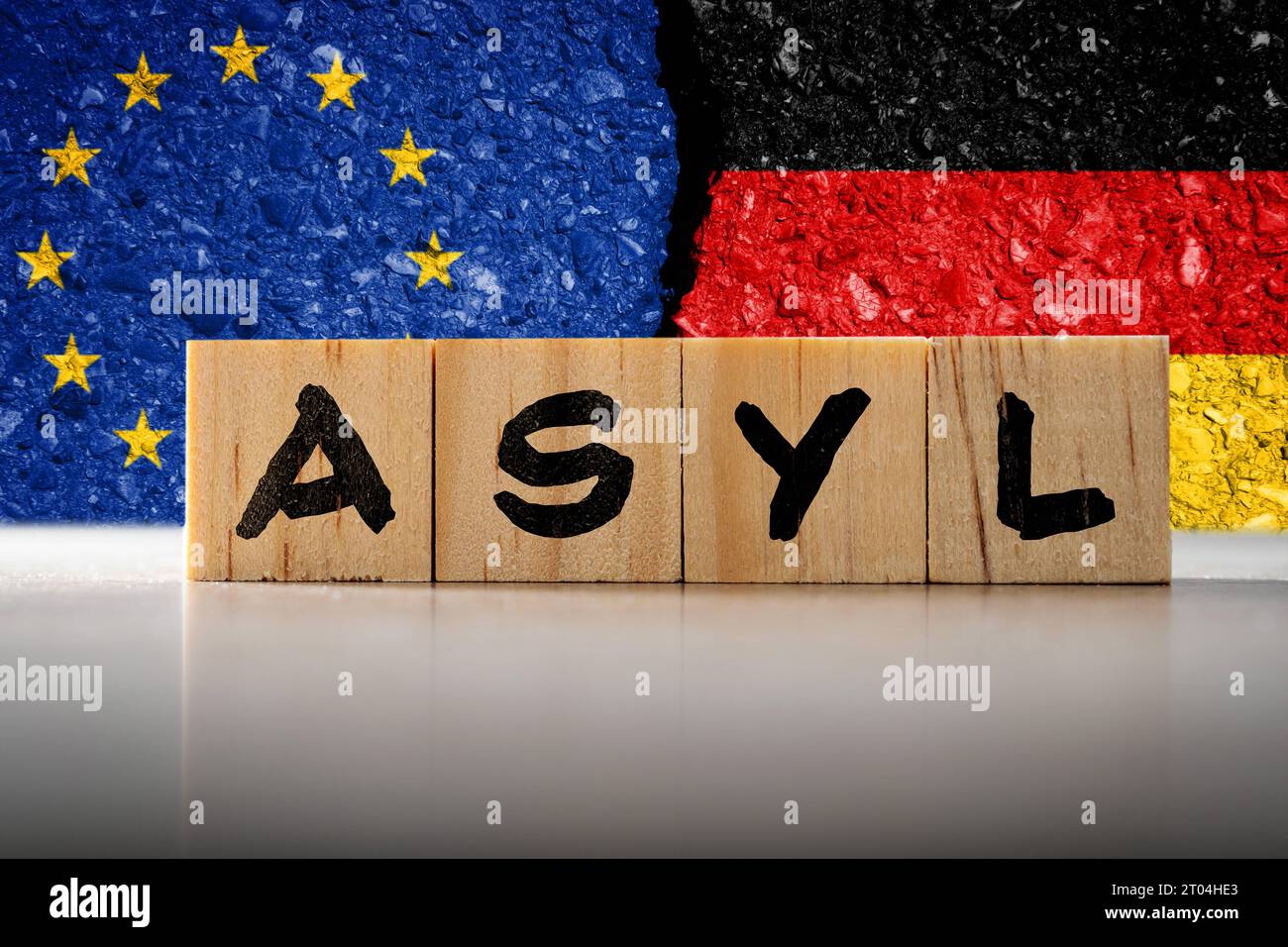 Wooden cube with inscription Asylum in front of broken wall with EU ...