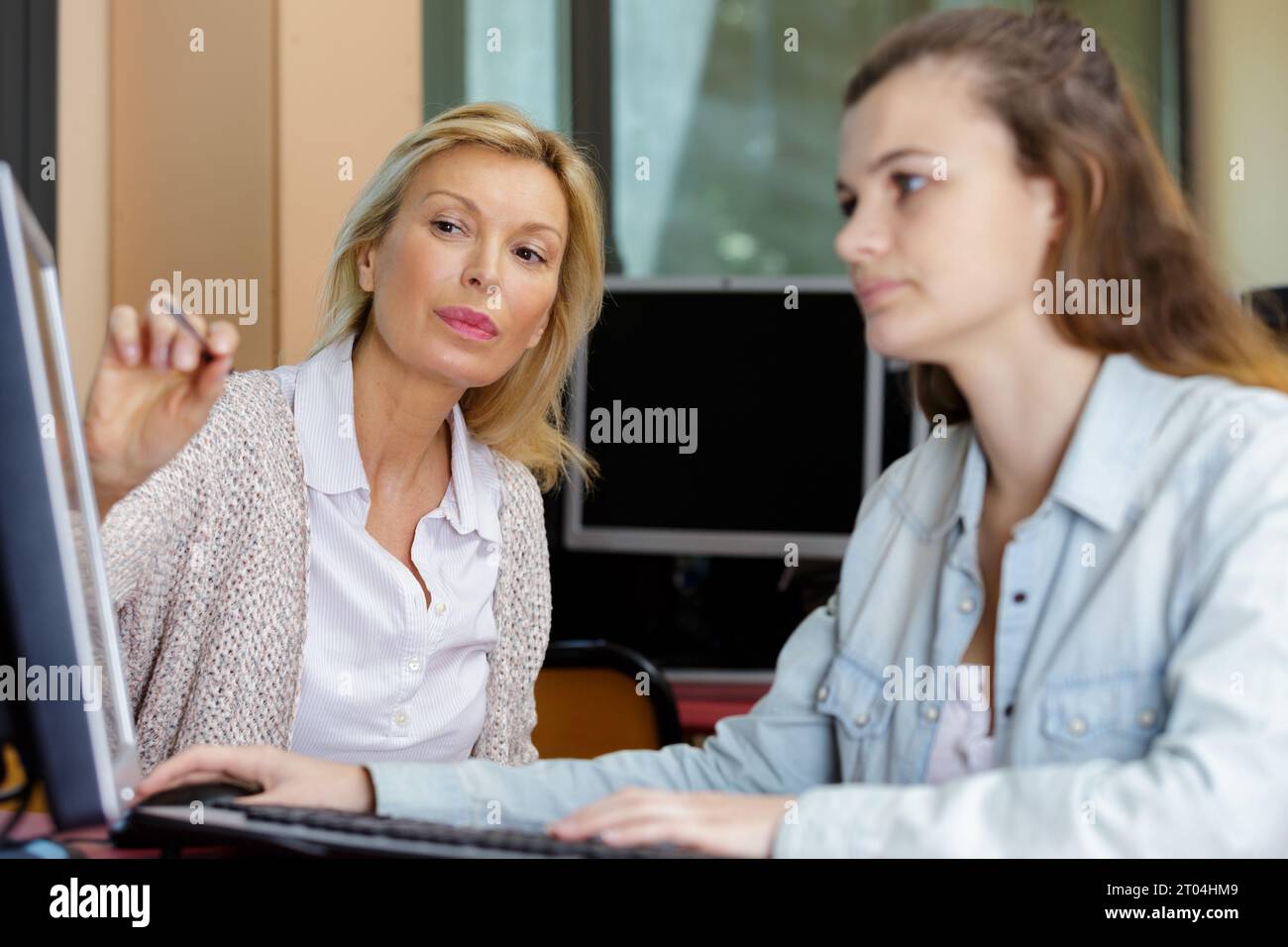 teacher helping female student using computer in classroom Stock Photo ...
