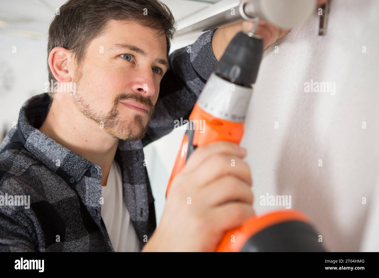man drilling a hole in the ceiling Stock Photo - Alamy