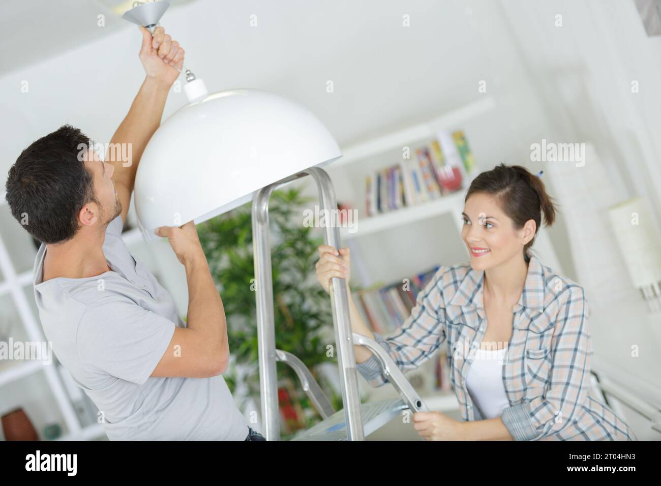 young couple installing lamp on ceiling Stock Photo - Alamy