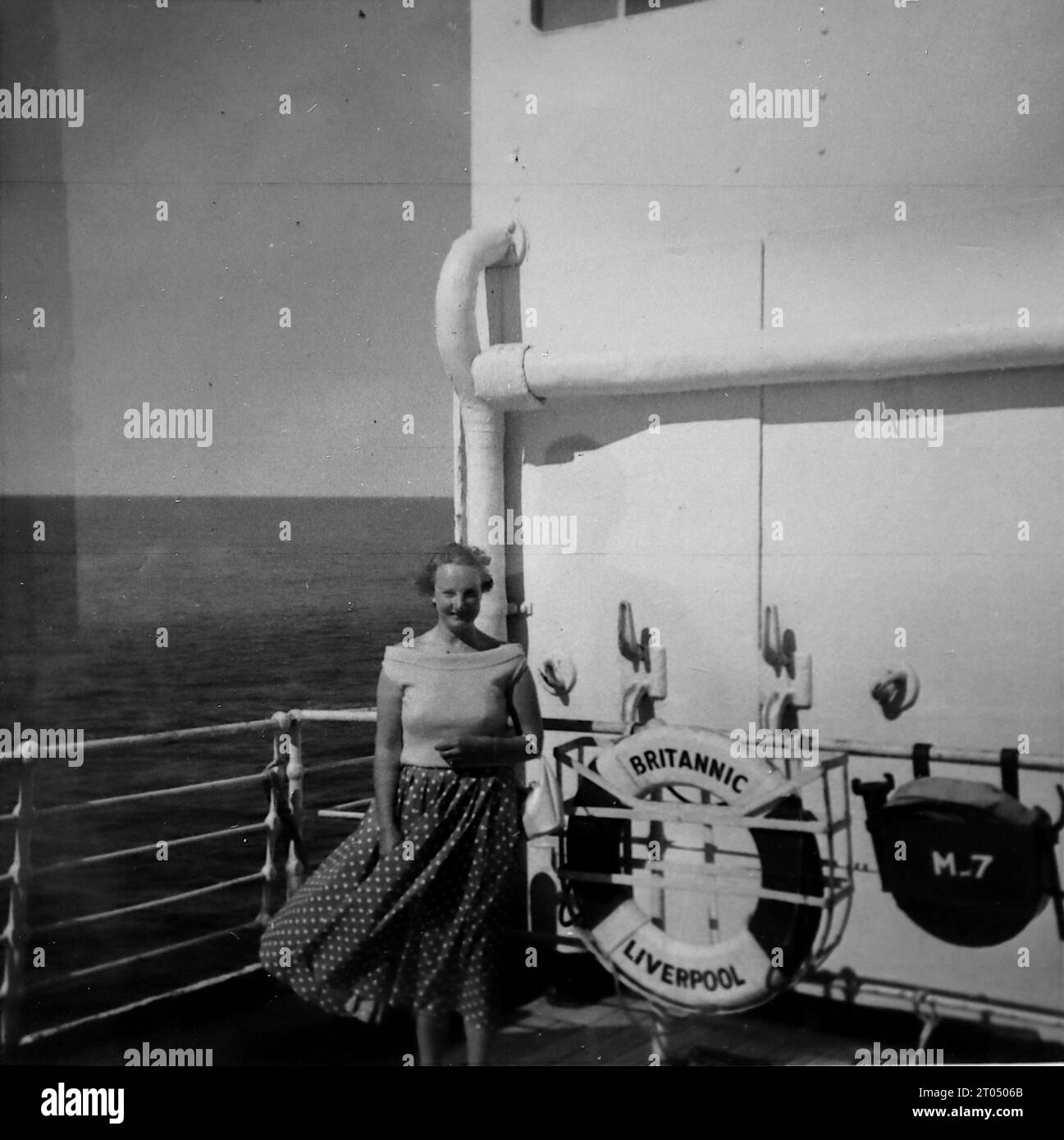 A lady passenger standing beside an M.V. Britannic life buoy. This ...
