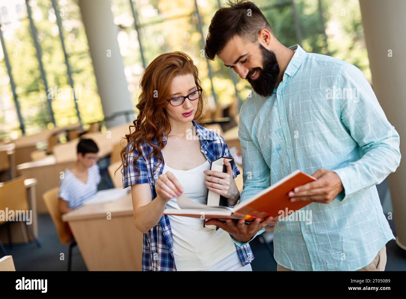 Happy university students studying with books in library. Group of ...