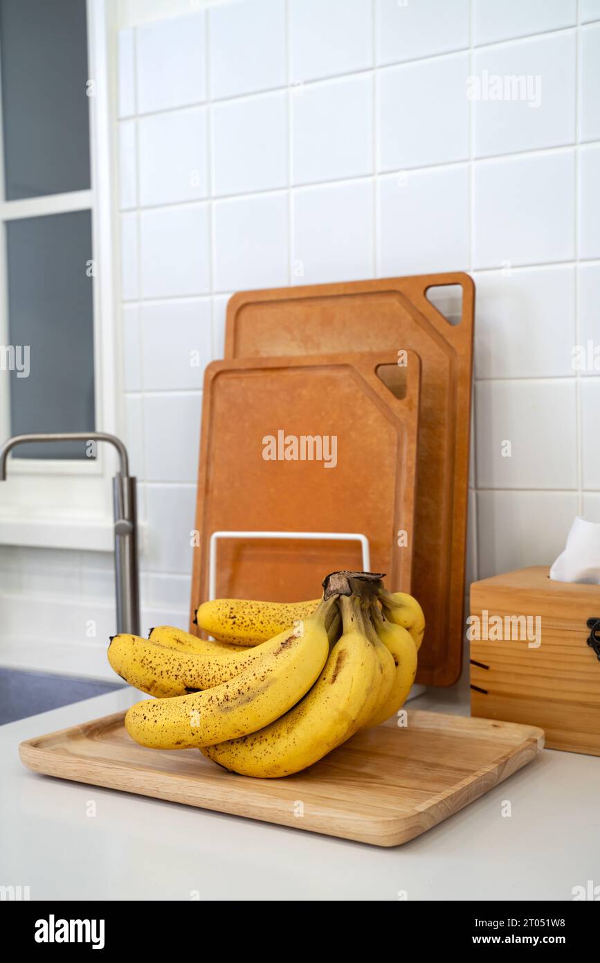 A bunch of fresh banana lie on the table in a modern kitchen, healthy ...