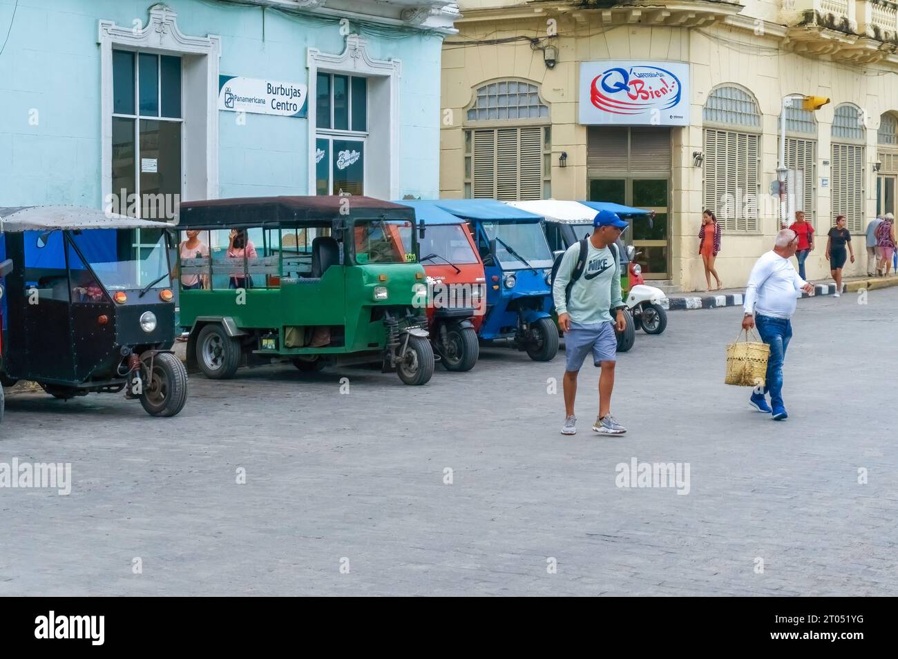 Cuban people in their routine lifestyle walk by a tricycle terminal in ...