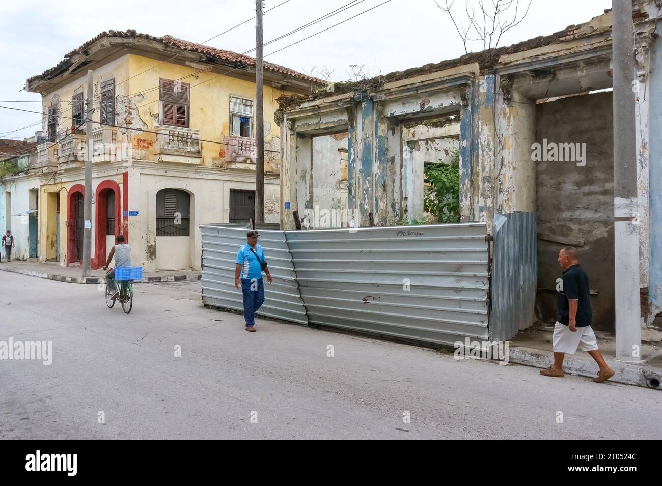 Cuban people walking by a collapsed old building in the Marta Abreu ...