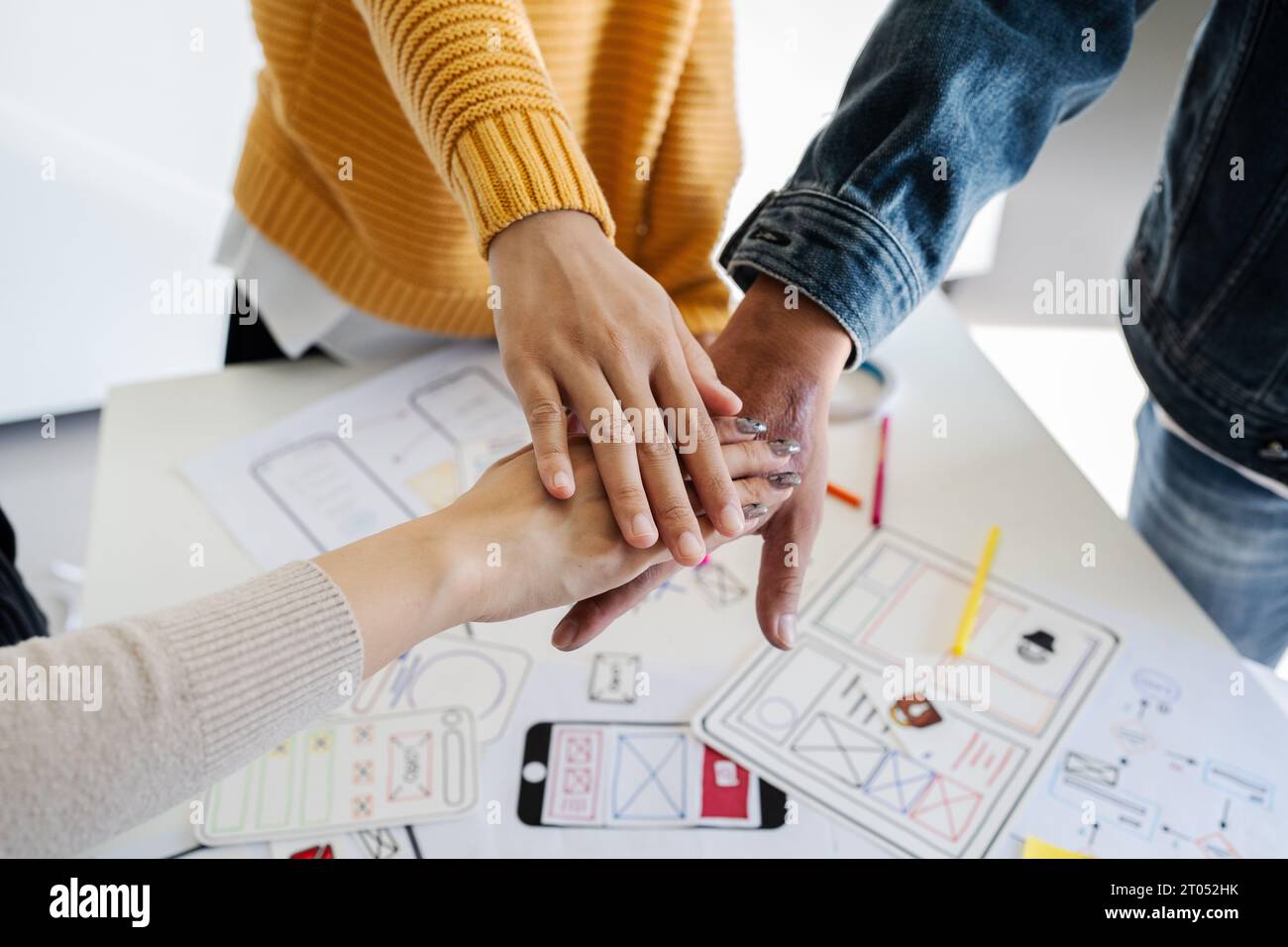 Asian ux developer and ui designer team stacking hands together ...