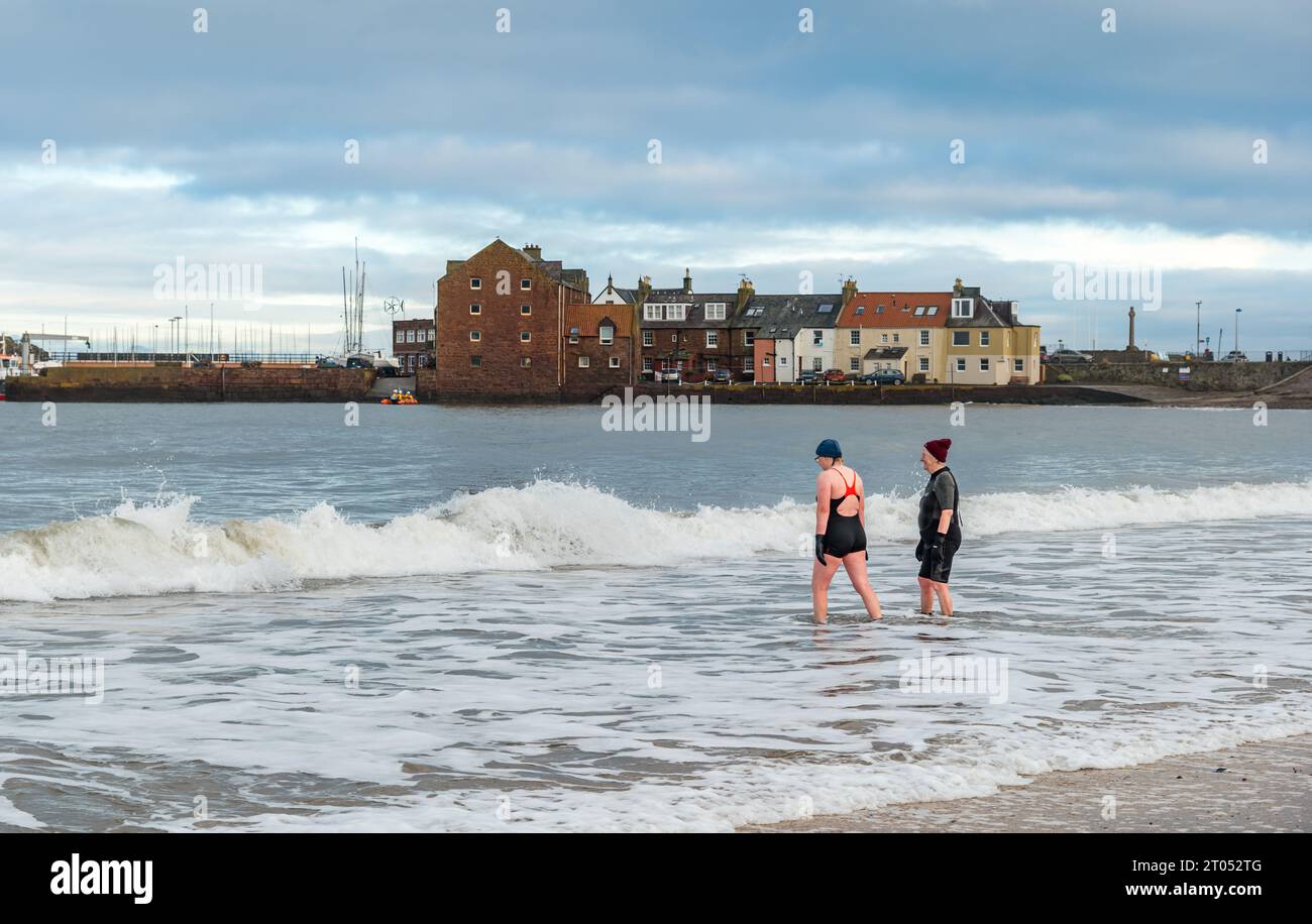 Two women going into water to wild swim, West Bay, North Berwick, East ...