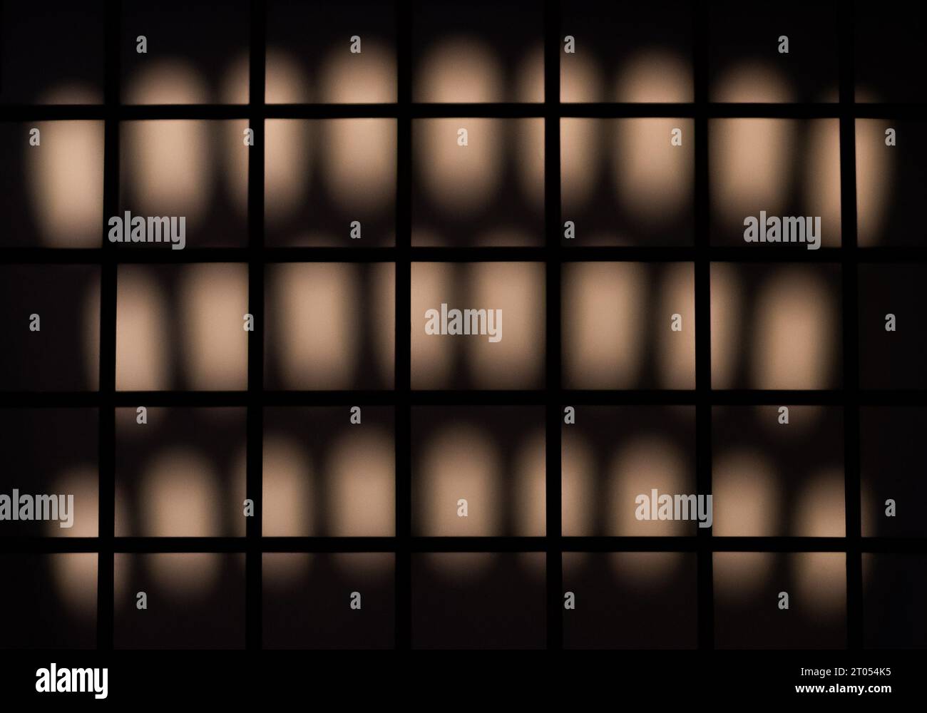 Closeup of a metallic grid or grate lit with a warm white light source ...