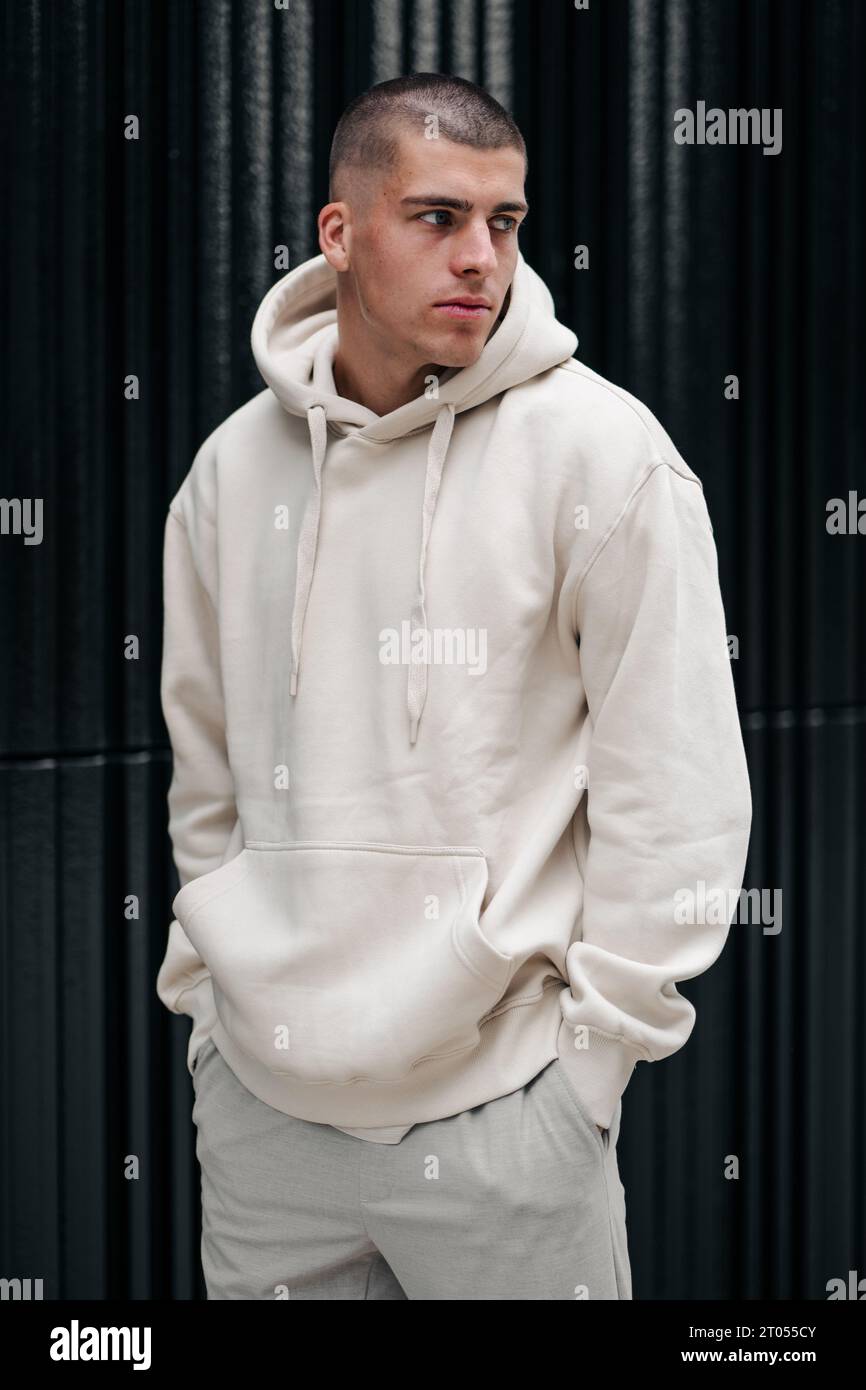 A young Caucasian male model wearing a white hoodie and posing on the ...