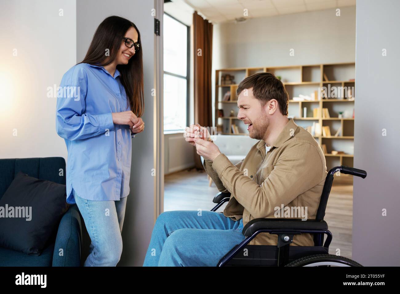 Man in wheelchair extend her hand palm up to side. Woman giving key ...