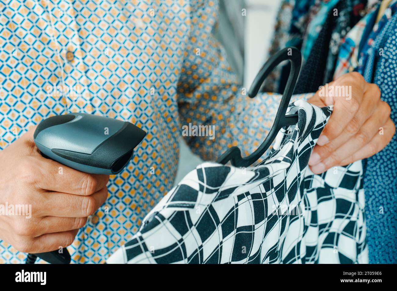 closeup of a shop assistant, in a clothes shop, scanning the barcode of ...