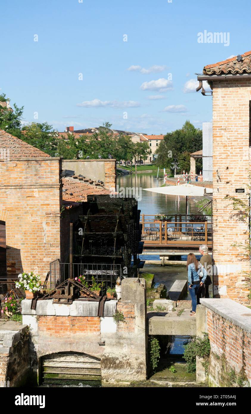 A young couple observes ancient Italian watermill in the small town of ...