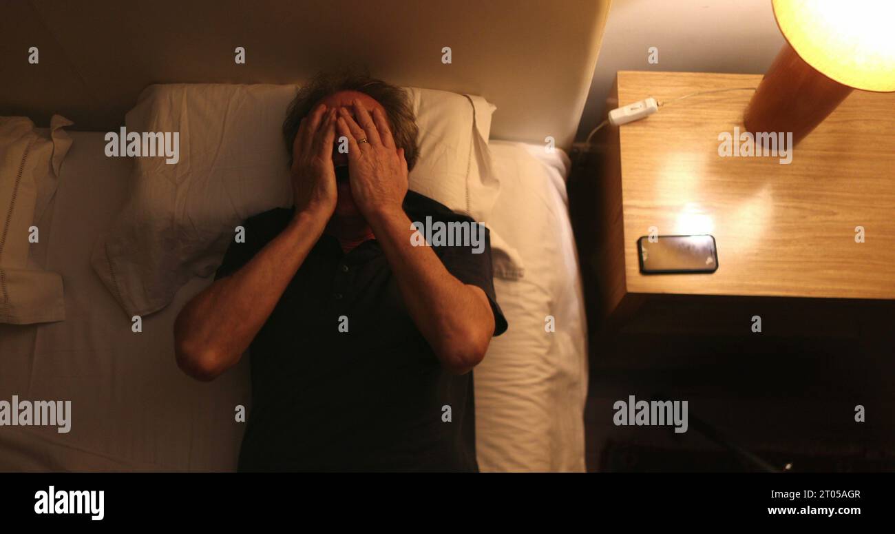 Tired old man rubbing eyes in fatigue, lying in bed, top view Stock ...