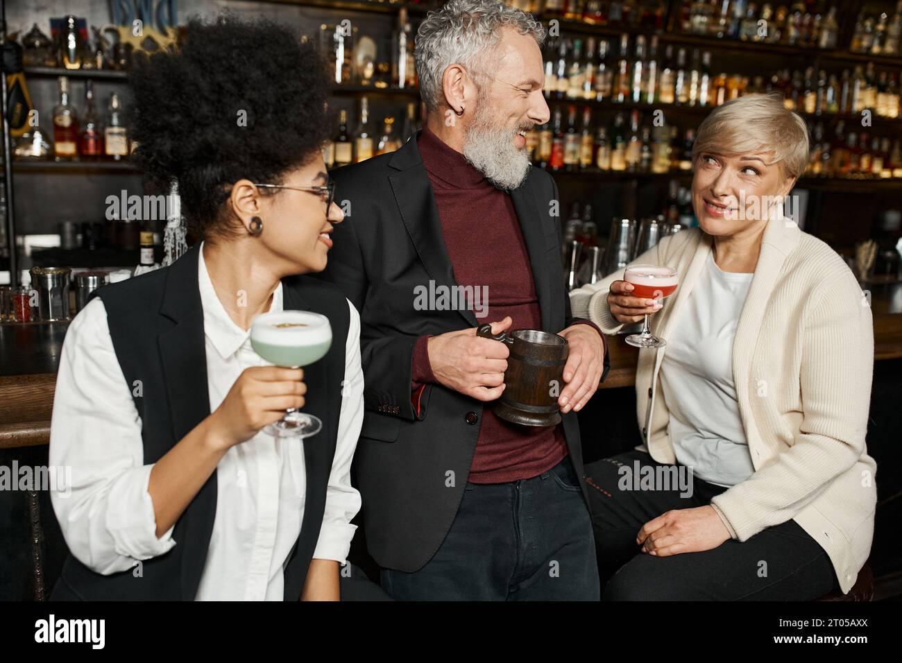 multiethnic women with cocktails glasses smiling during conversation ...