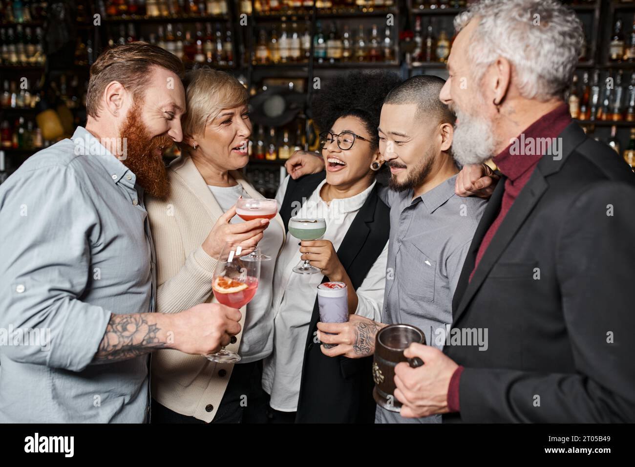 joyful multicultural colleagues holding glasses with drinks and talking ...