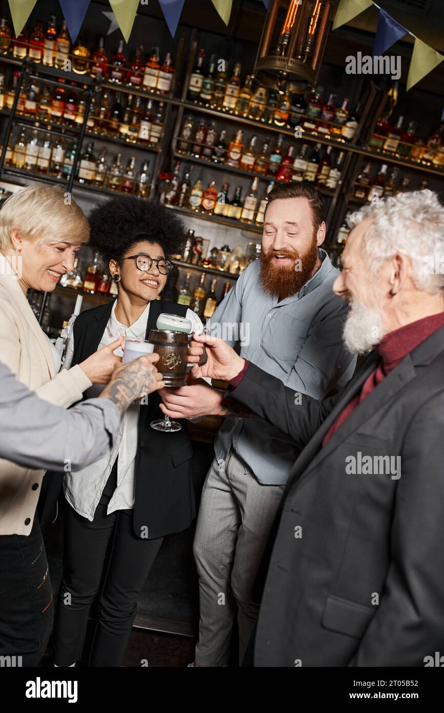 joyous multicultural colleagues toasting with drinks during after work ...