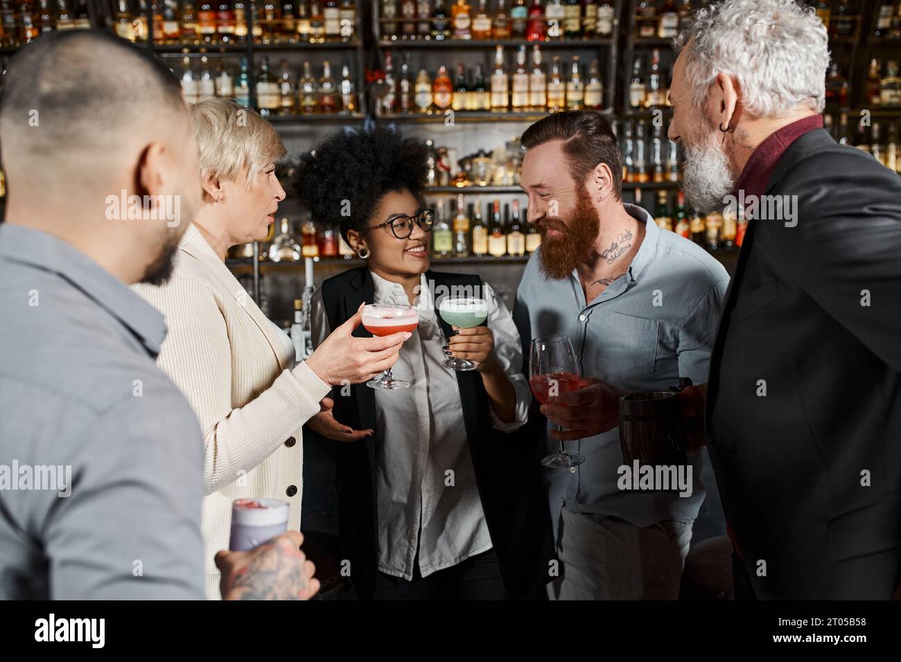 multiethnic colleagues with drinks smiling during conversation in bar ...