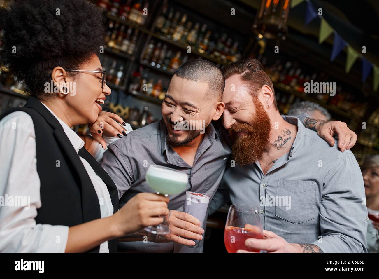 bearded men and african american woman laughing in cocktail bar ...