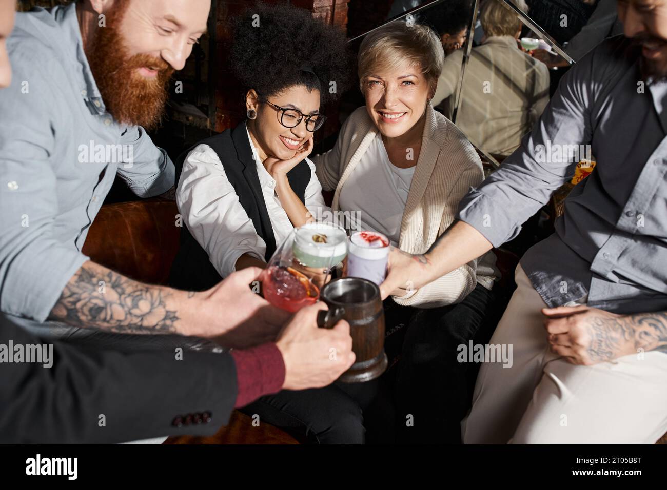 cheerful multiethnic colleagues clinking glasses with cocktails while ...