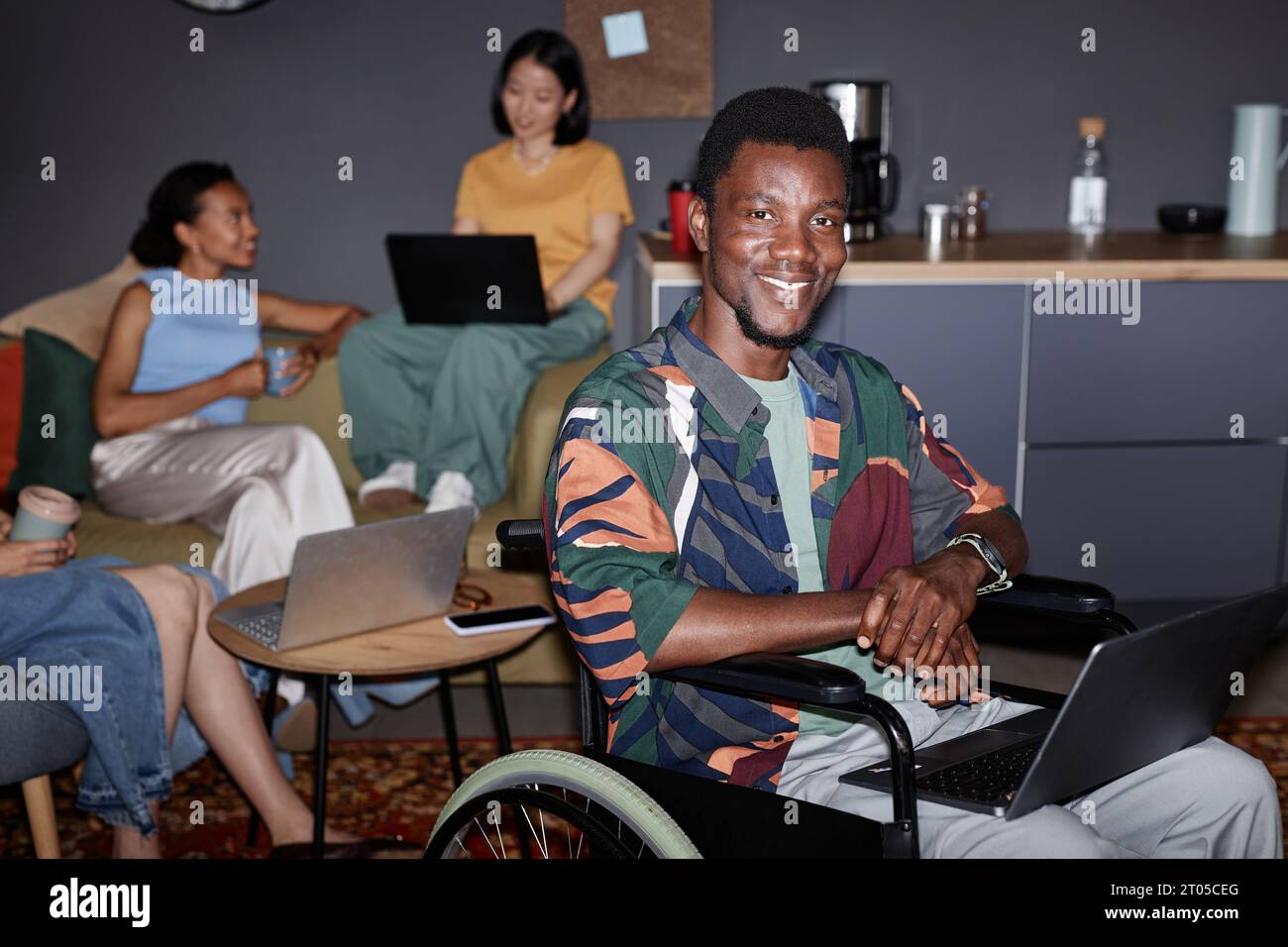 Portrait of young Black man with disability smiling at camera in modern ...