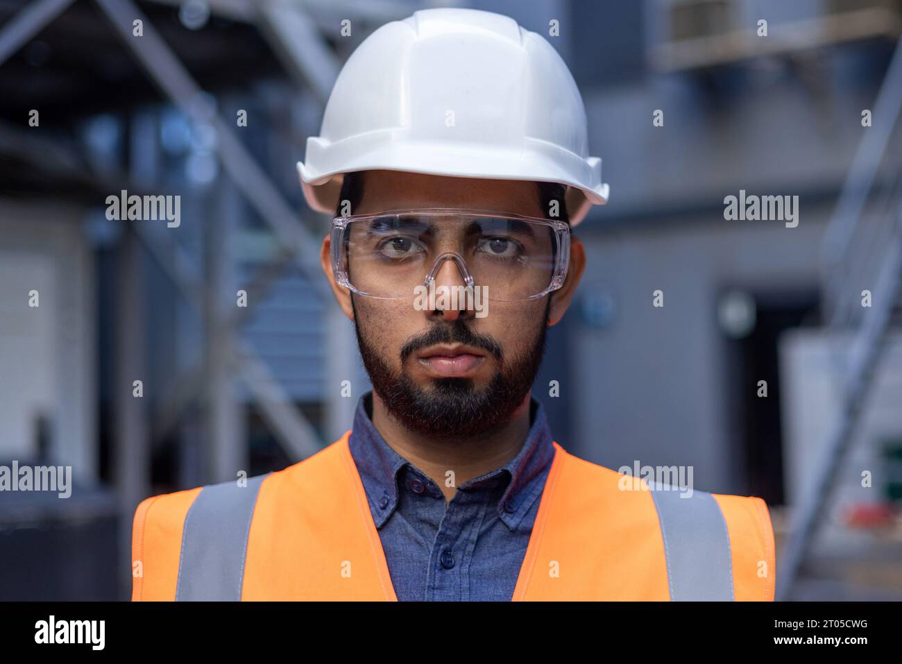 Close-up portrait of a young male engineer wearing a hard hat and vest ...