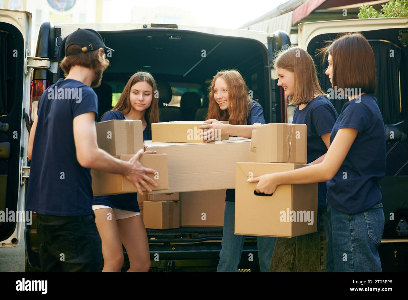 Group of young people, man and women, volunteers loading many boxes of ...