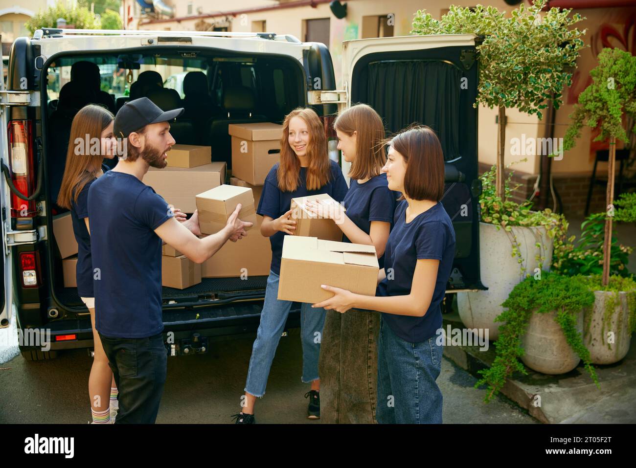 Group of young people, man and women, volunteers loading many boxes of ...