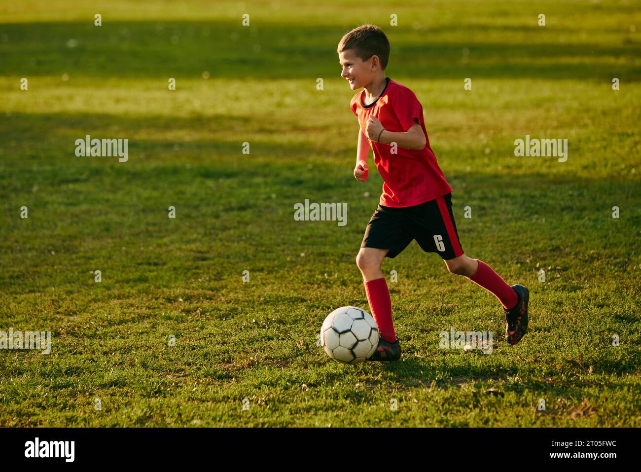 Boy soccer player in red sport uniform throwing ball out of side line ...