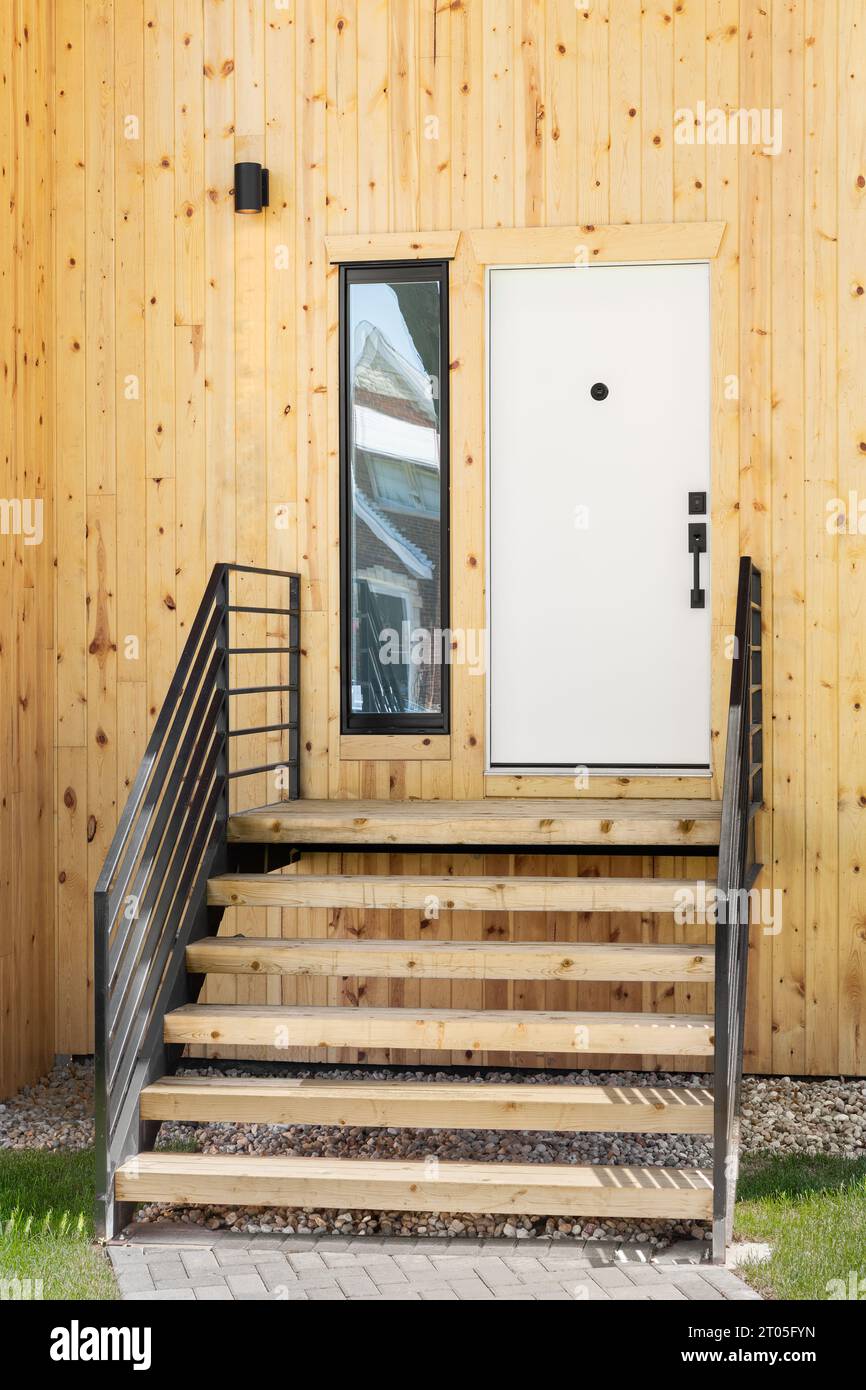 The front door of a home with a natural wooden siding and wrought iron ...
