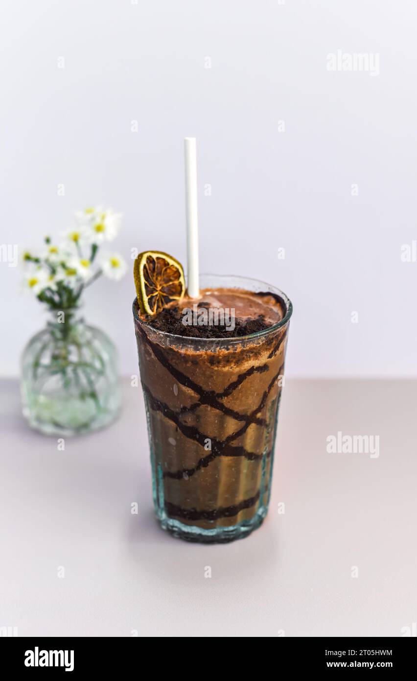 Cacao drink with banana and peanut butter on a table with vase of ...